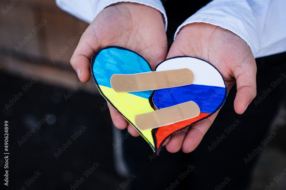 Ukrainian and Russian flags together in broken heart in child hands ...