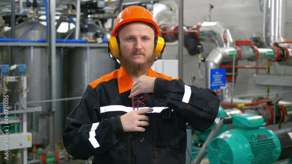 Industrial operator man with a beard in an orange helmet, headphones ...