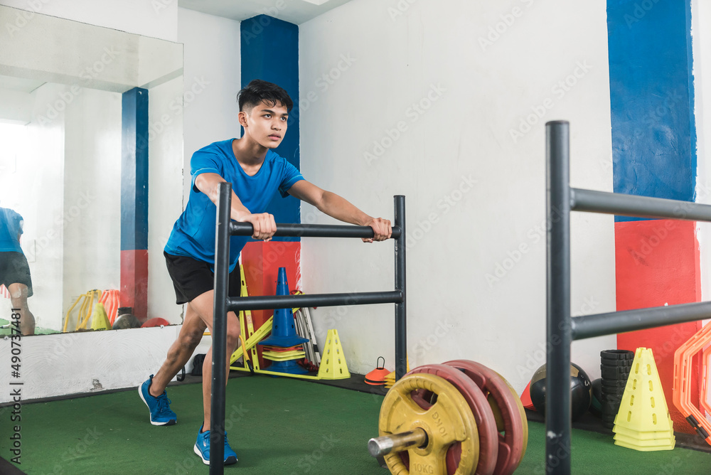 Foto de A young asian man uses a sled push at the gym. A prowler sled ...