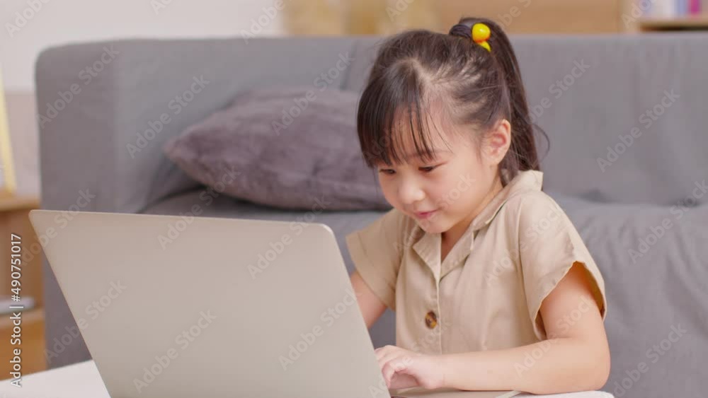 Adorable little girl sitting using computer laptop playing game and ...