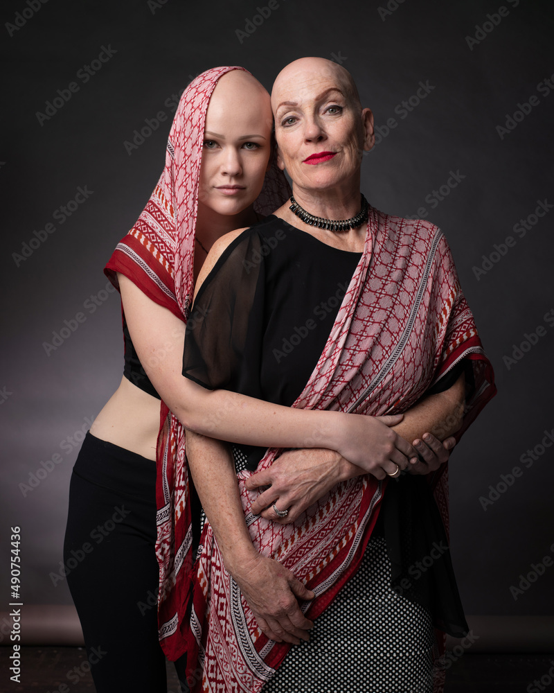 Two beautiful women posing together with a red scarf in a studio ...