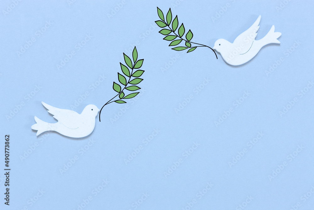 Two white figurines of a doves of peace with olive tree branch in their ...