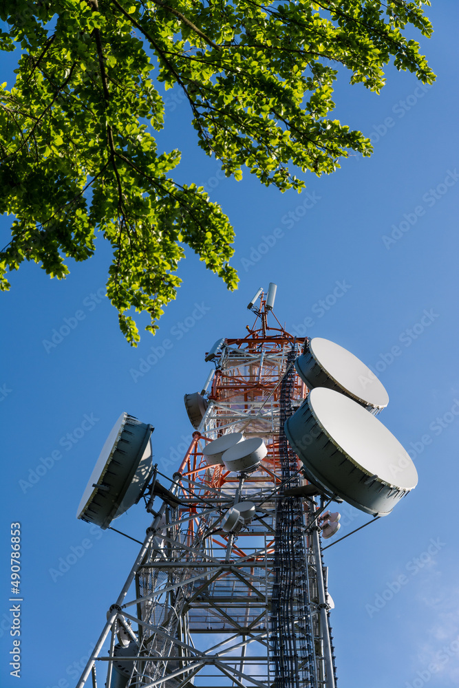 Parabolic antennas on steel communications tower under blue sky with ...
