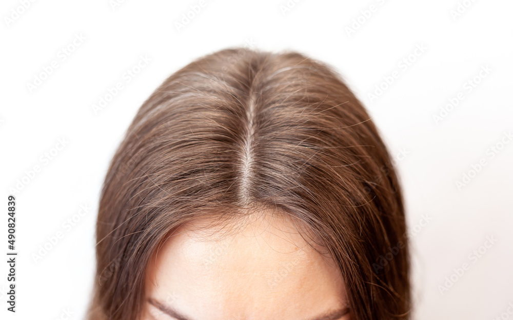 A woman's head with a parting of gray hair that has grown roots due to ...