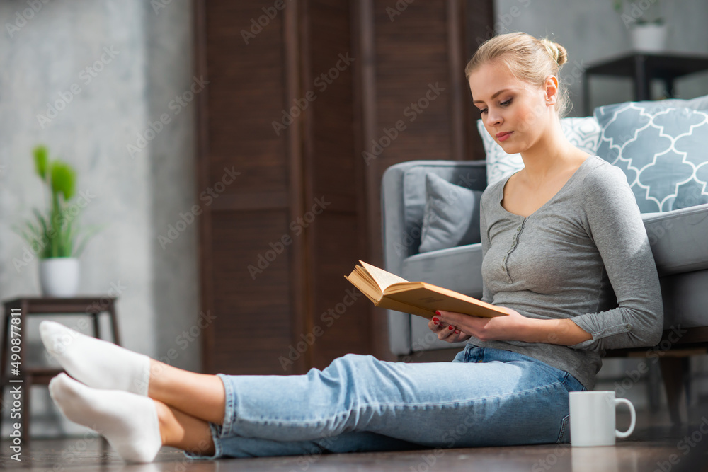 Young blonde girl is reading a book or a textbook. A beautiful woman is ...