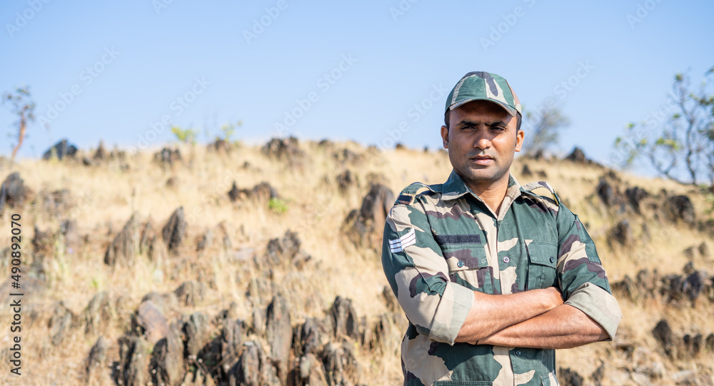 Confident smiling indian soldier in uniform standing with arms crossed ...