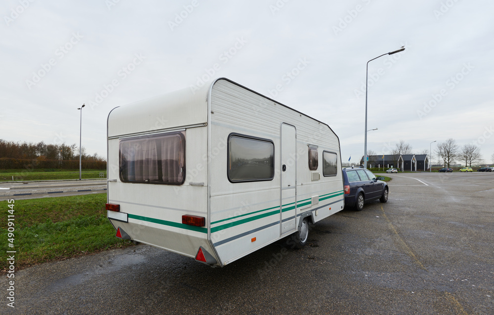 Foto de Caravan trailer and a car parked near the empty highway through ...