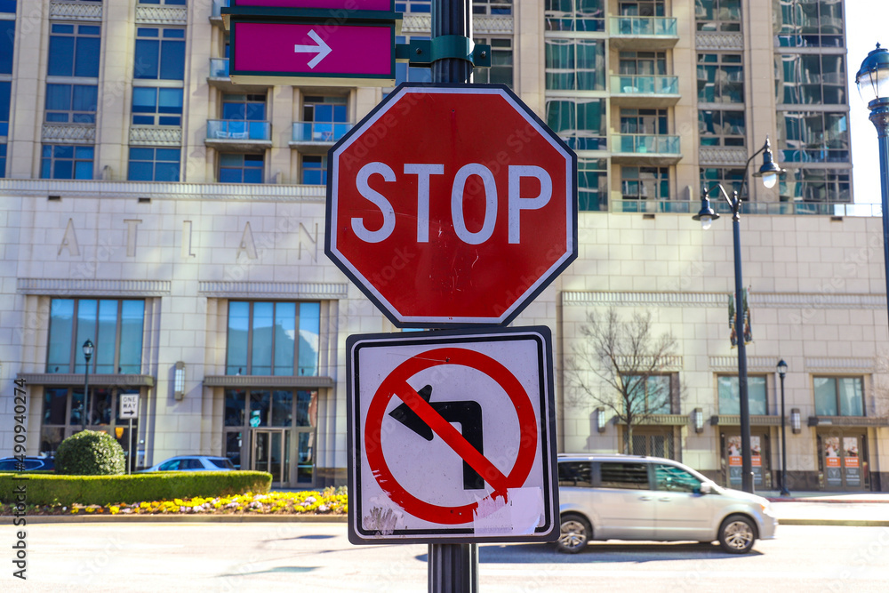 a red and white stop sign with a no left turn sign on a tall black pole ...