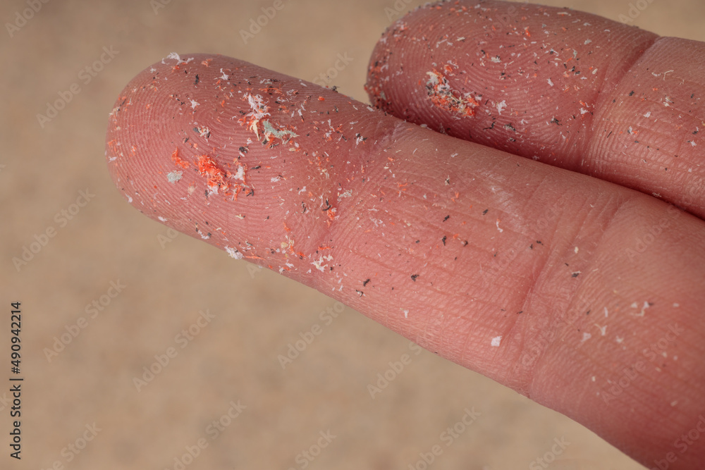 Close-up of microplastics lay on finger of human being. Small plastic ...