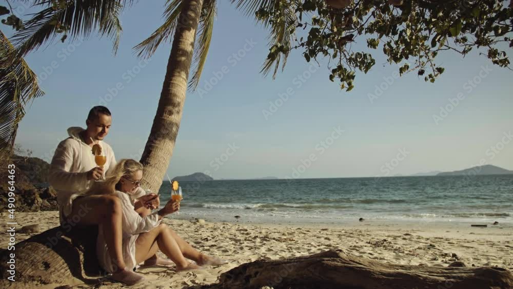 Cute loving couple in white dress and sunglasses, near palm tree, relax ...