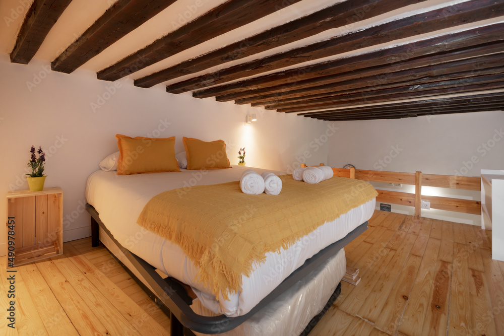 Attic of a house with a pine wood structure with a king size bed, a ...
