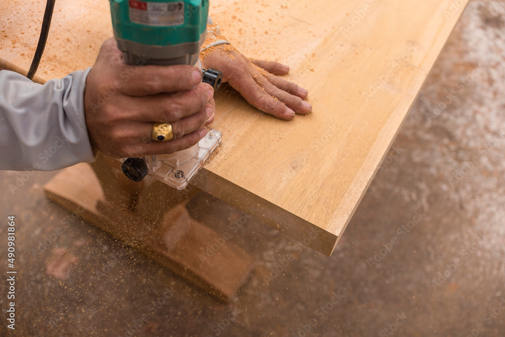 A carpenter uses a laminate trimmer to carefully bevel or smoothen the ...