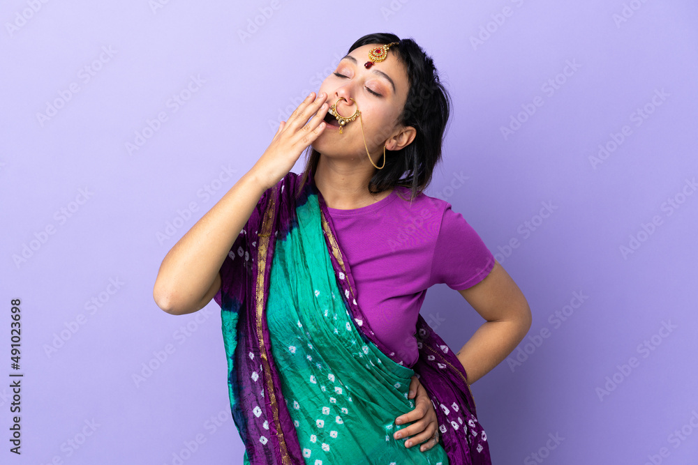 Indian woman isolated on purple background yawning and covering wide ...