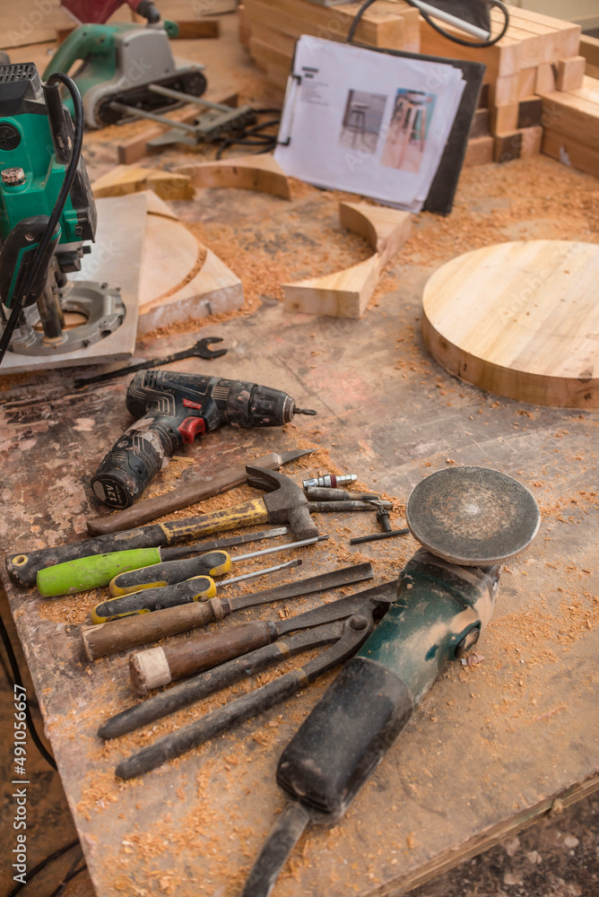 Woodworking tools on a table filled with sawdust. Drills, a hammer ...