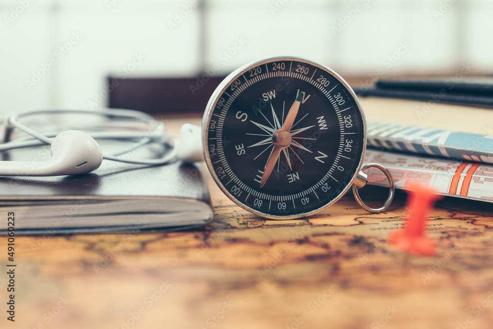 Magnetic compass and marking with a red pin on routes on world map ...