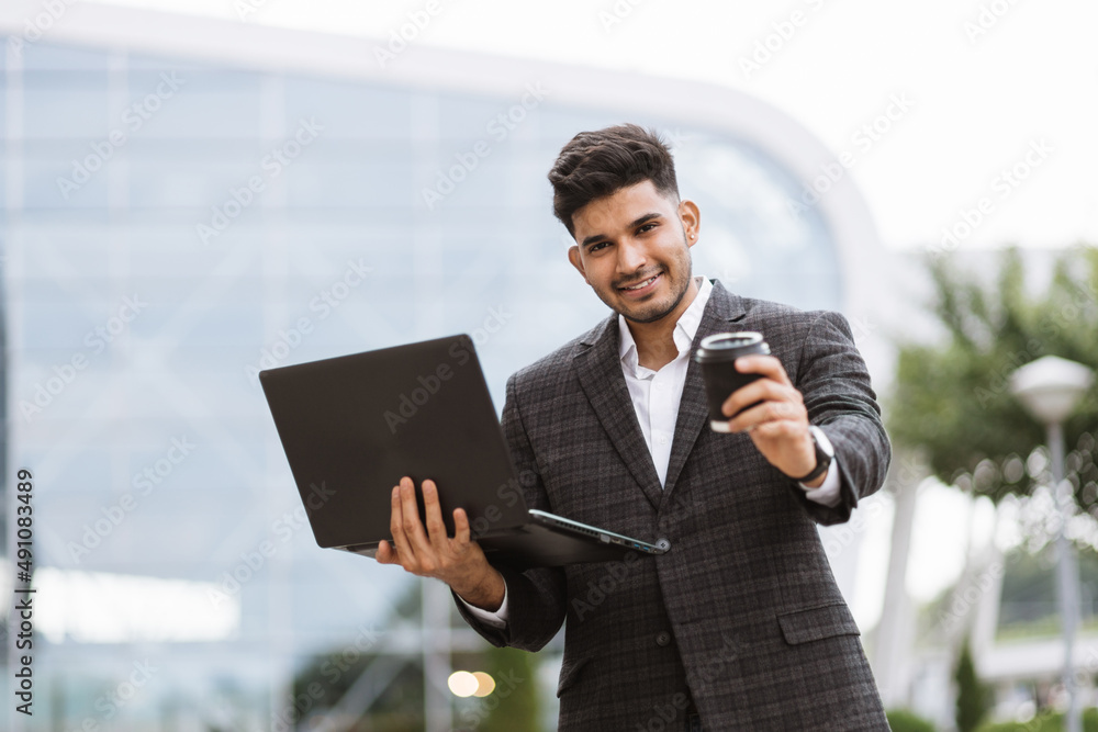 Young male asian indian economist using laptop and drinking coffee to ...