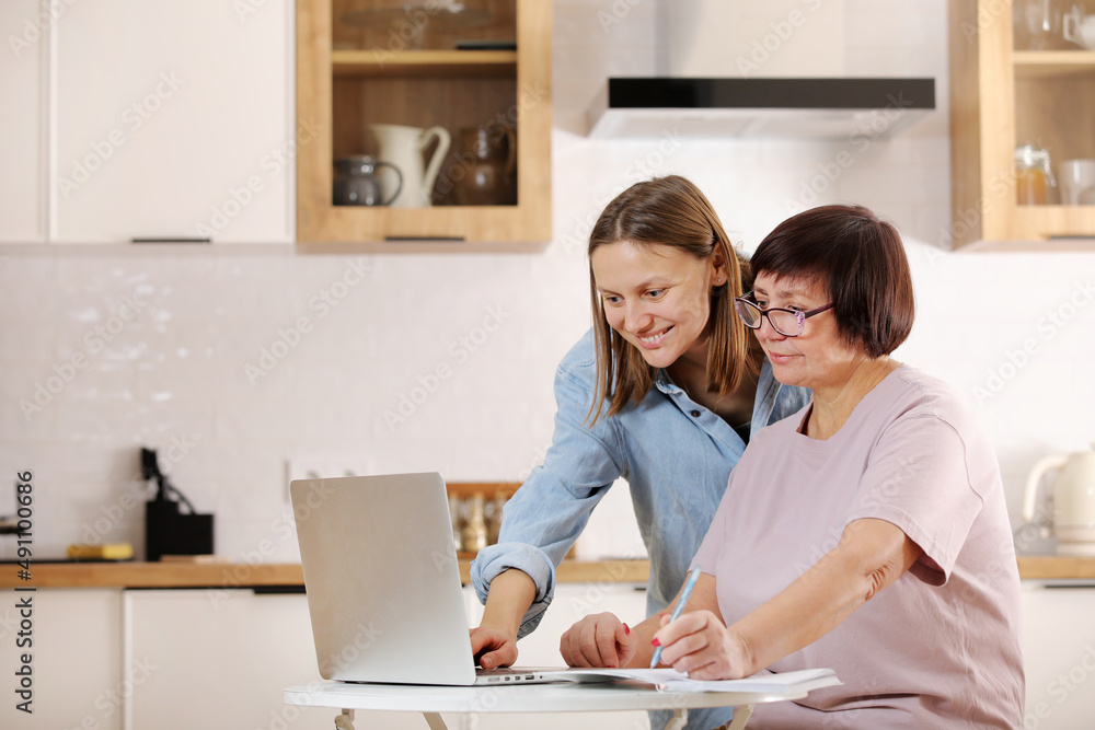 young woman teaching senior mother to use internet on laptop at home ...