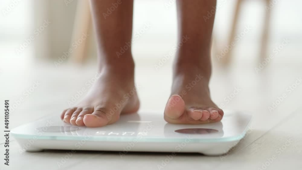 Legs of black girl standing on scale to measure weight. African ...