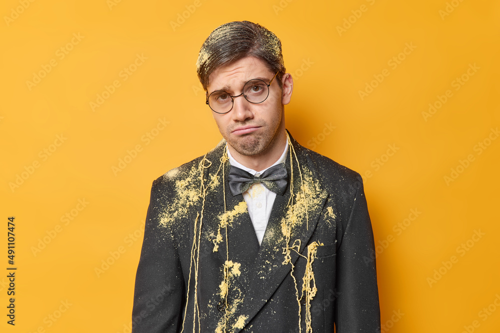 Portrait of displeased young European man looks sadly at camera frowns ...