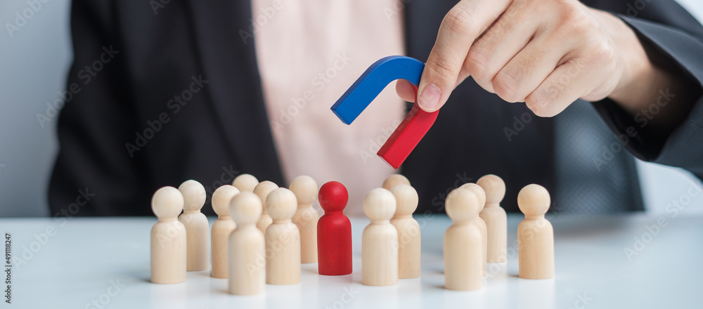 Business woman hand holding magnet and pulling man wooden figure from ...