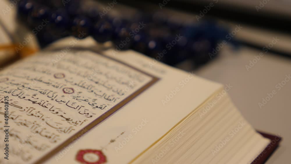 A moving shot showing an opened Quran, and the prayer beads leaned on ...
