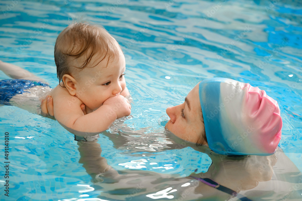 Early age swimming in pool. Baby boy trained to swim in water. Happy ...