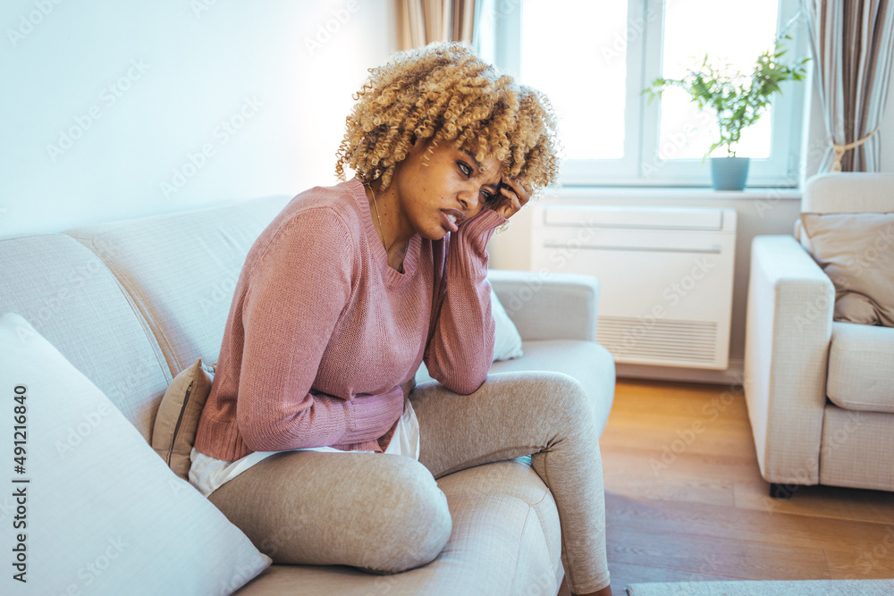 Woman Sitting On Sofa Suffering From Stomach Pain. Unhealthy young ...