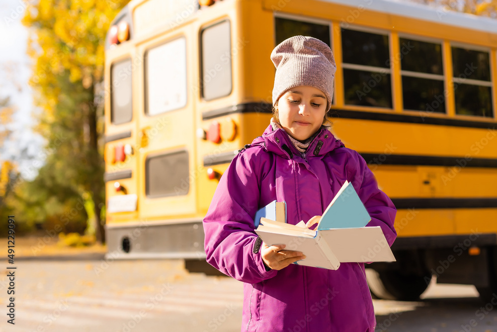 Little girl standing by a big school bus with her books. Stock Photo ...