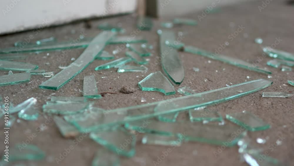 Multiple pieces of broken glass from a window lying on a floor ...