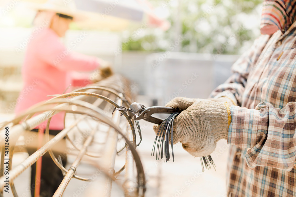 Construction worker hands securing steel bars with wire rod for ...