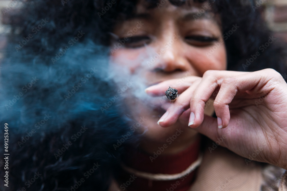 Smiling young woman smoking cigarette Stock Photo | Adobe Stock