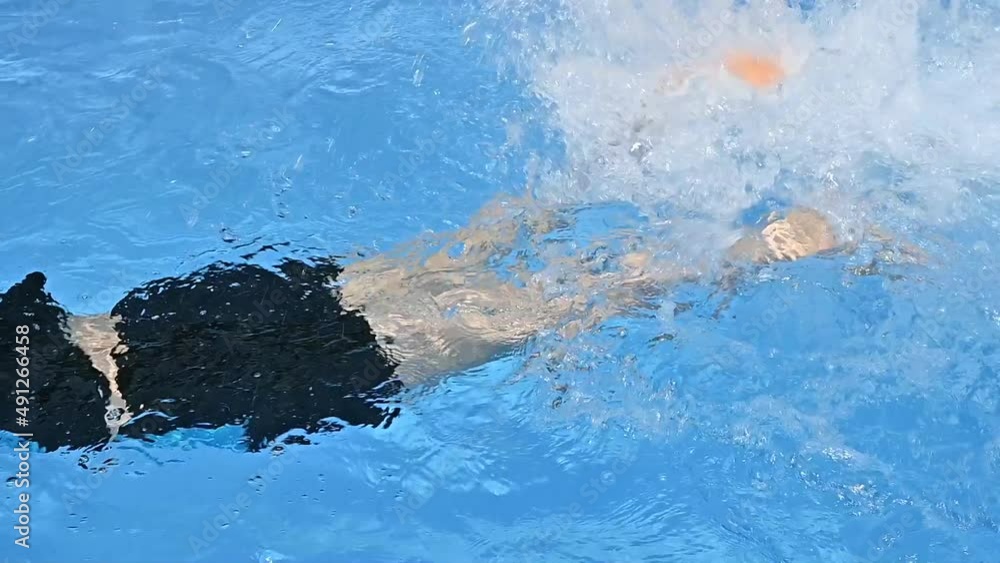 Woman swimming in swimming pool by kicking water surface for moving ...