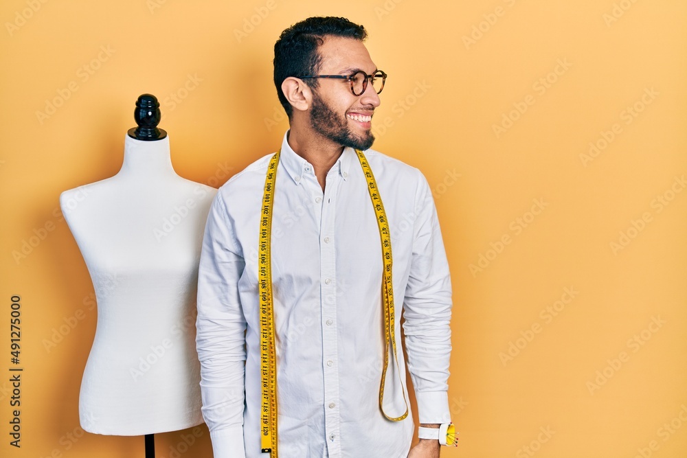 Hispanic man with beard dressmaker designer standing by manikin looking ...