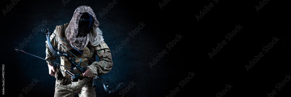 Unrecognizable silent killer with a compound bow in military uniform ...