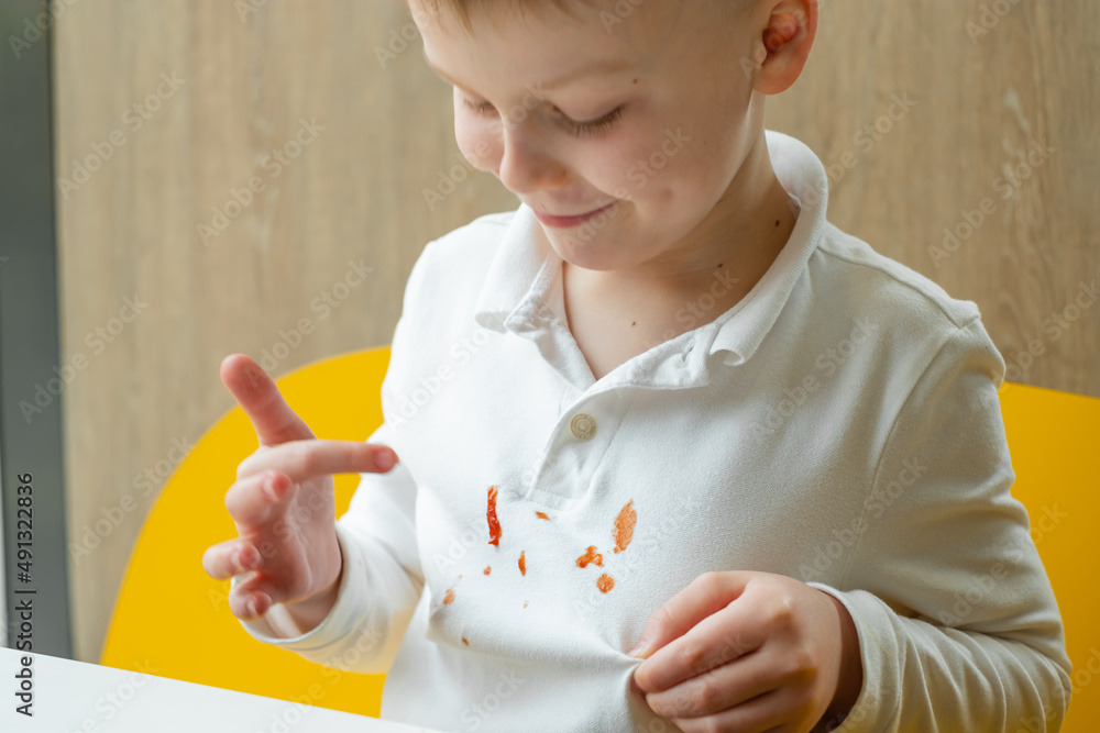 The child showing points a finger at the ketchup stain on clothes ...