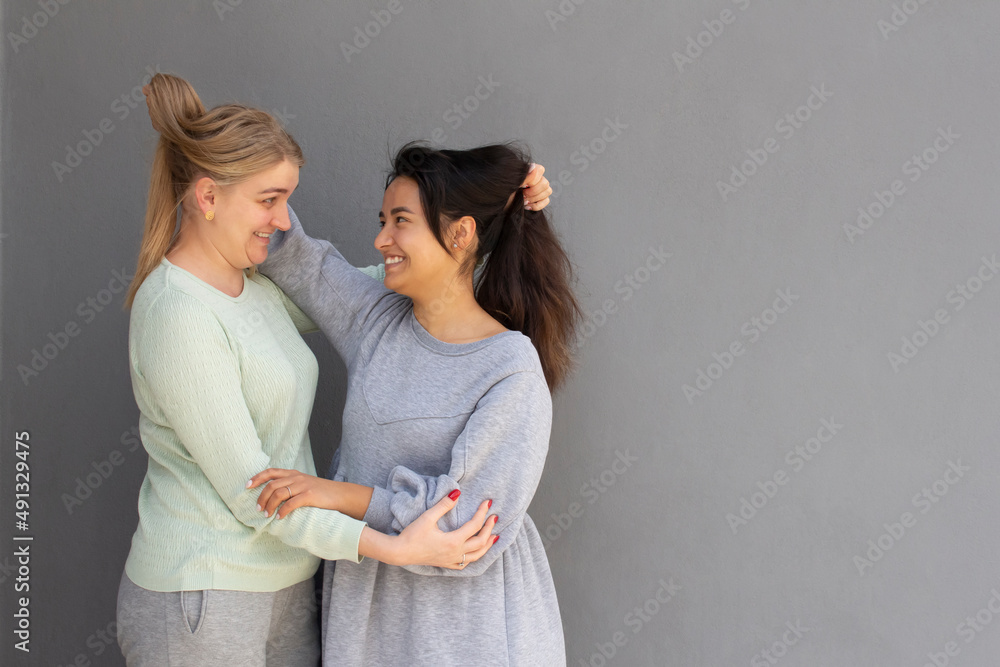 two girls with different color of hair are standing and hugging each ...