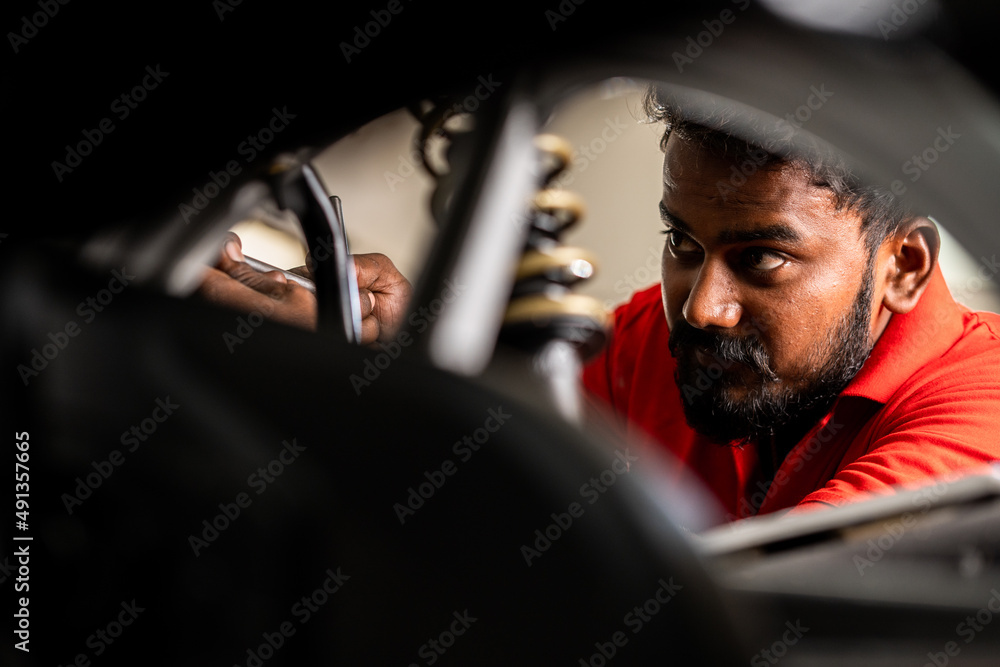 handheld close up head shot shot of bike mechanic reparing motorbike at ...