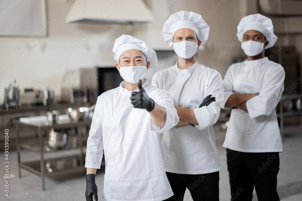 Portrait of multiracial team of three chefs standing together in the ...