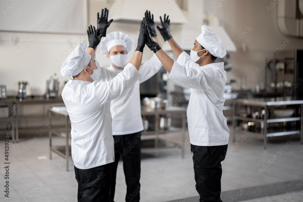 Multiracial team of chefs giving five with hands cheering each other ...