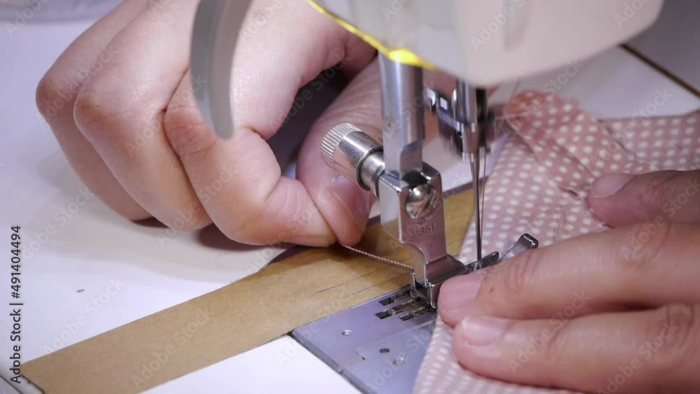 Needle on sewing machine moving up and down while fingers push light ...