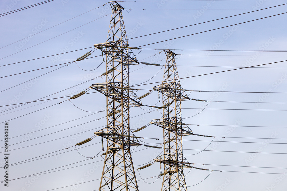 High voltage power lines pylons and electrical cables on a clear blue ...