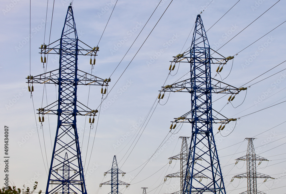 High voltage power lines pylons and electrical cables on a clear blue ...