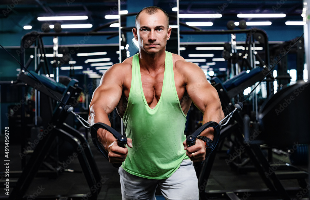 Brutal handsome Caucasian bodybuilder working out training in the gym ...
