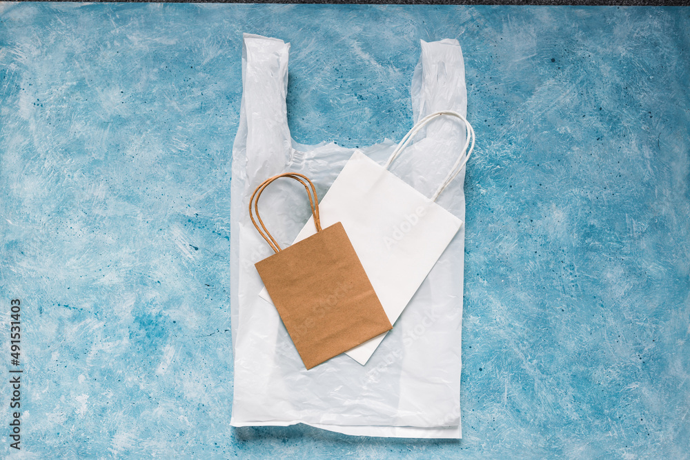 single use plastic bag next to paper ones, plastic pollution and ...