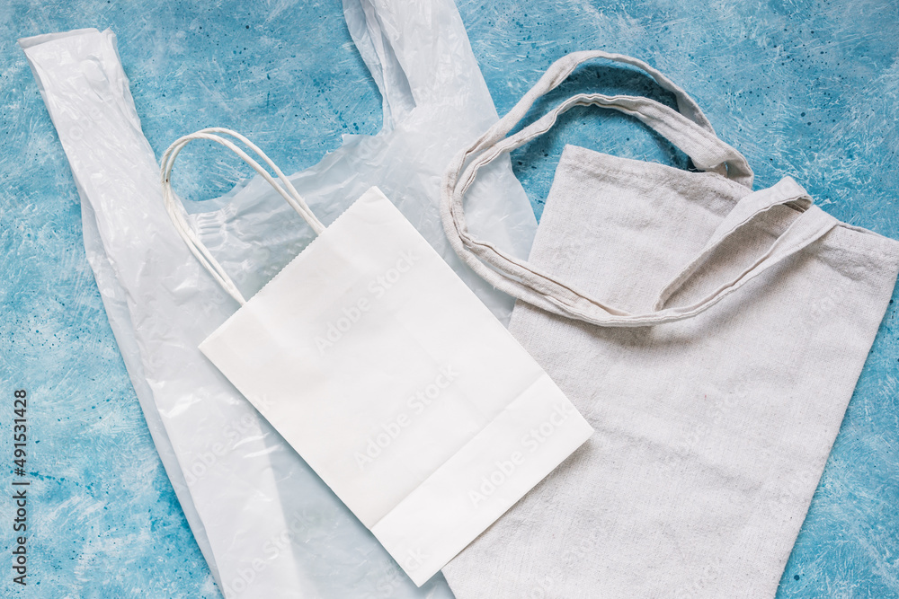 single use plastic bag next to paper and reusable canvas ones, plastic ...
