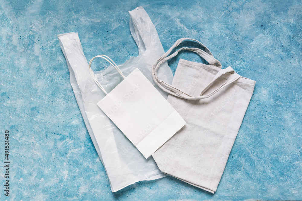 single use plastic bag next to paper and reusable canvas ones, plastic ...