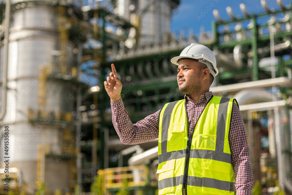 Asian engineer man with white safety helmet standing front of oil ...