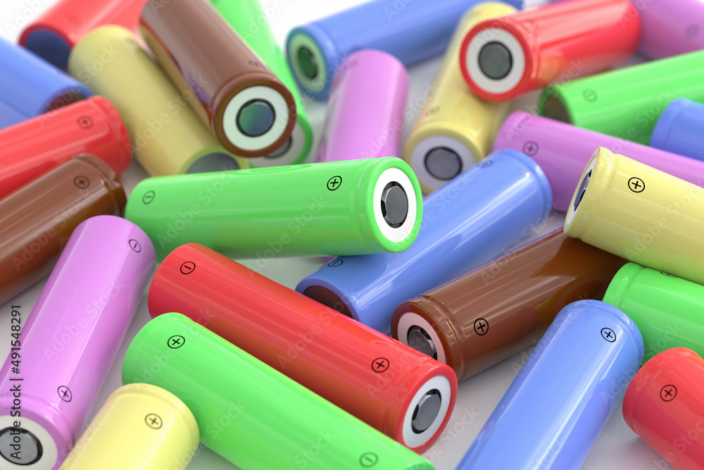 Lots of cylindrical batteries of different colors scattered on a white ...