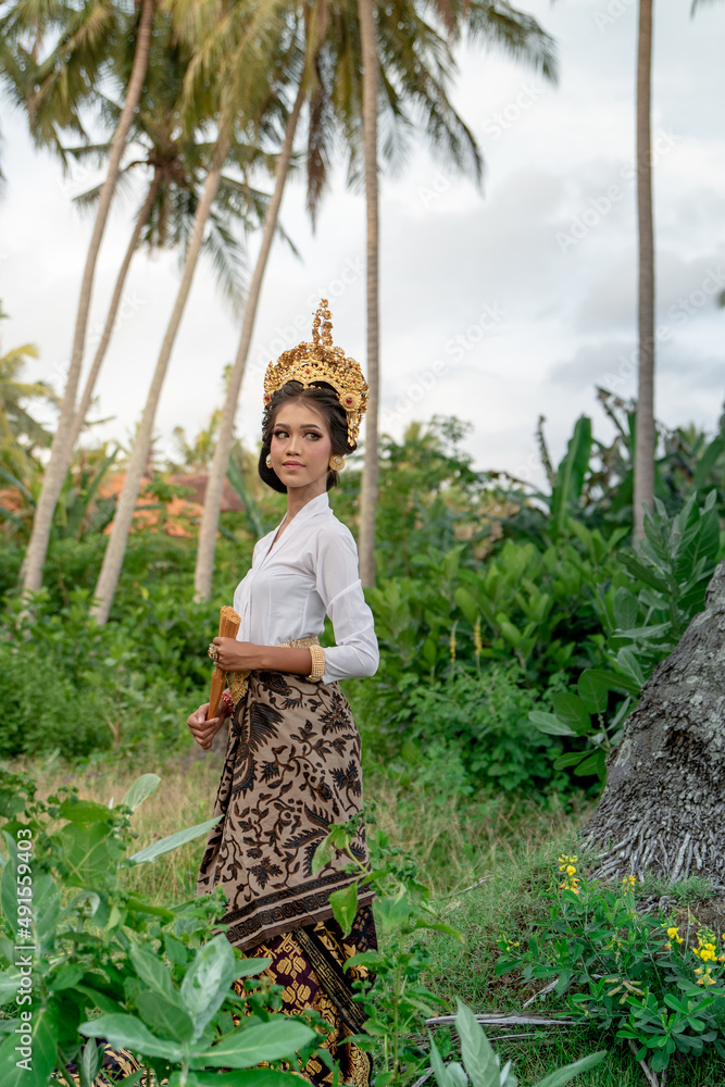 Portrait of a Balinese young girl in traditional dress and in a palm ...
