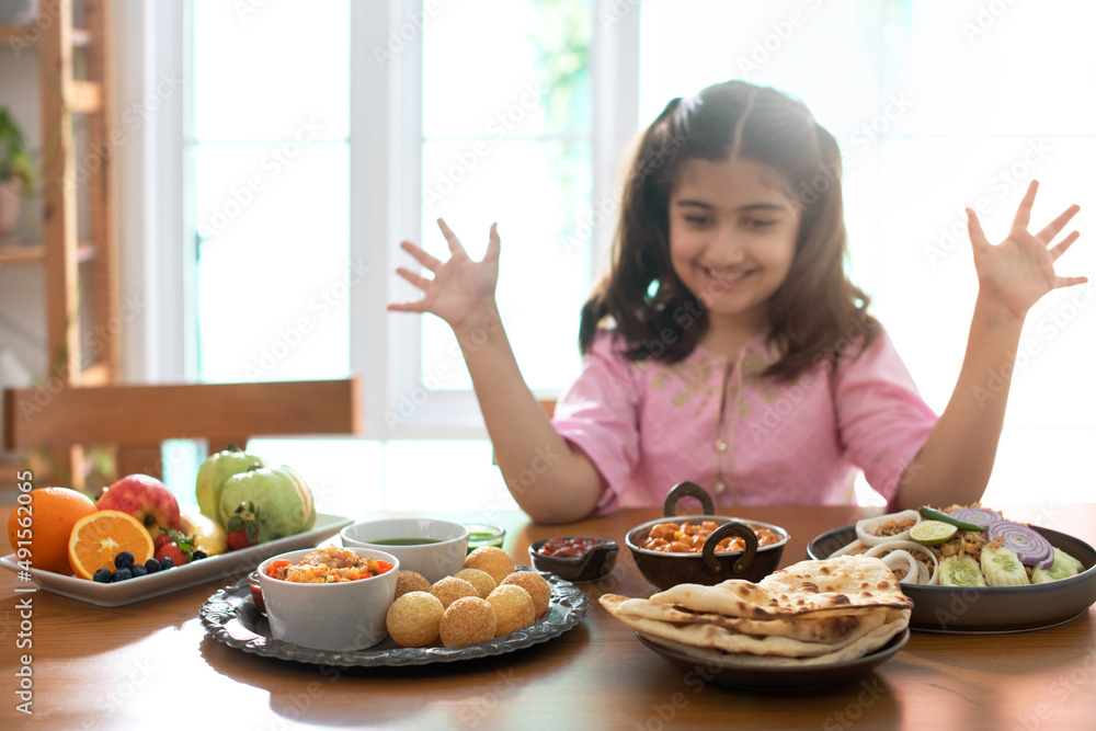Cute little Indian girl is enjoying her favorite Indian food, surprised ...